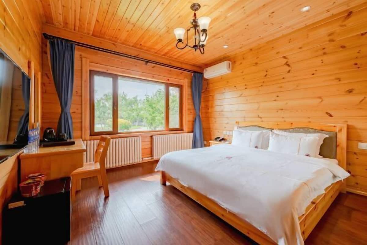 Quarto de cabana de madeira com uma cama grande, uma escrivaninha e uma cadeira.