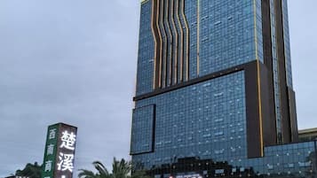 Um edifício alto com fachada de vidro moderna e um letreiro vertical bem visível à esquerda.
