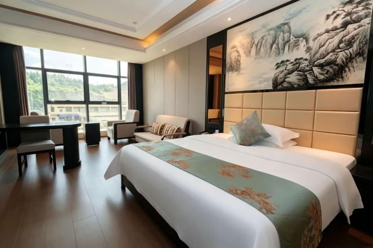 Quarto de hotel com uma cama grande, uma escrivaninha e vista para o exterior.