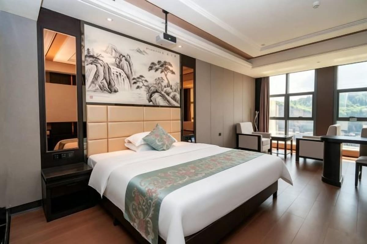 Quarto de hotel com uma cama grande, uma escrivaninha e vista para o exterior.
