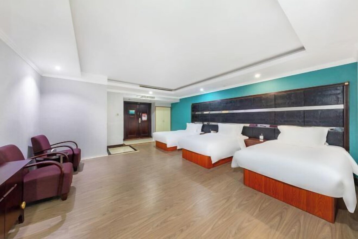 Quarto de hotel com duas camas, uma escrivaninha e cadeiras.