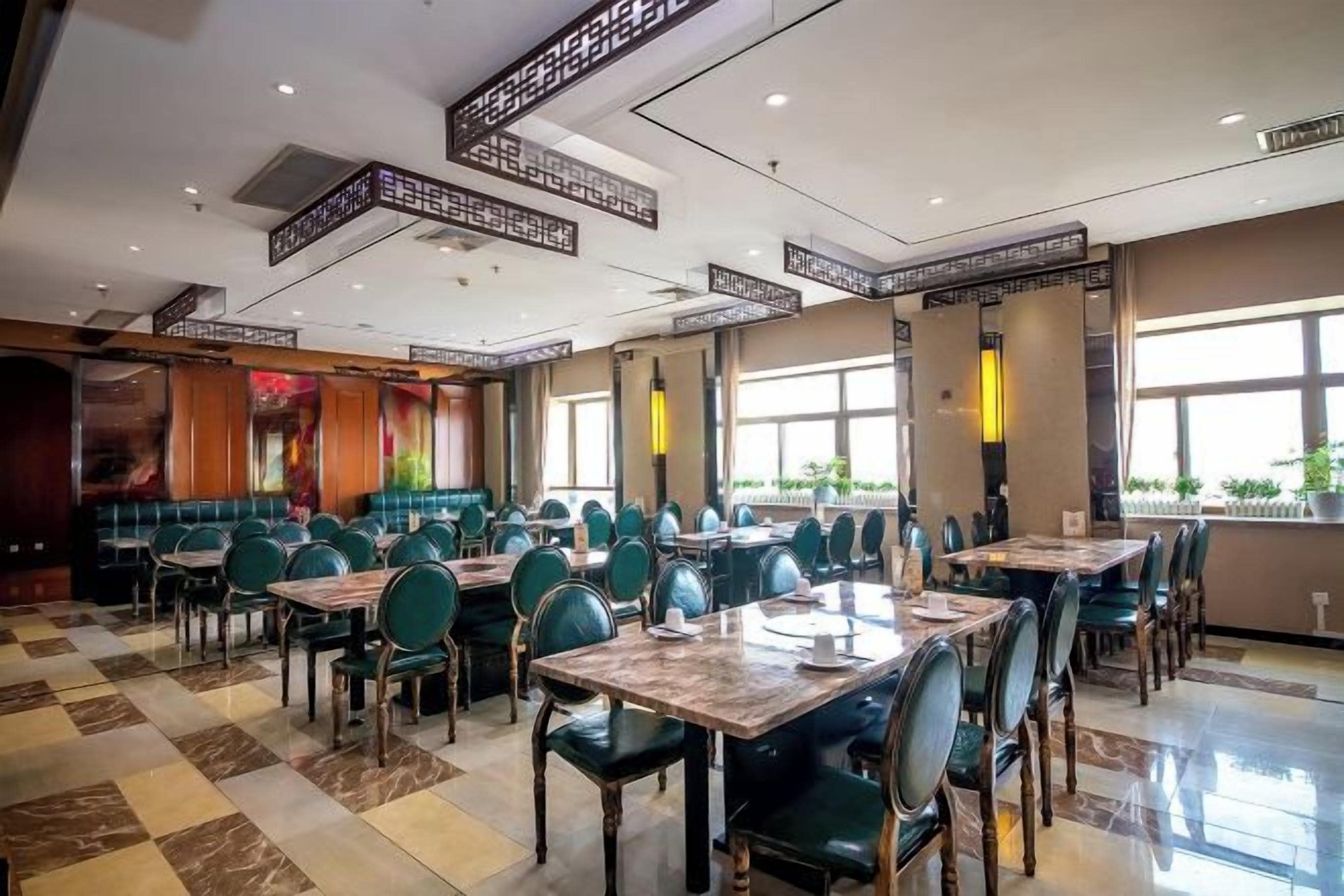 Restaurante com várias mesas e cabines para refeições, piso xadrez e grandes janelas.