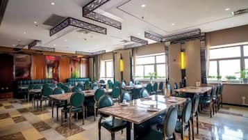 Restaurante com várias mesas e cabines para refeições, piso xadrez e grandes janelas.