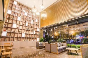 Um lobby moderno com uma grande estante, área de estar e amplas janelas.