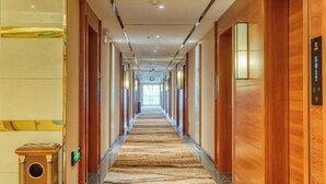 Corredor de hotel com portas de madeira, carpete estampado e uma placa indicando o quarto 5017.