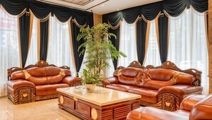 Uma sala de estar luxuosa com um amplo sofá de couro marrom, uma mesa de centro de madeira e uma grande planta em vaso.