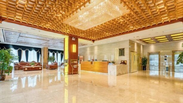 Um hall amplo com balcão de recepção, área de estar e teto decorativo.