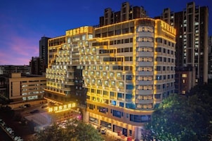 Um hotel com vários andares e design moderno, com uma entrada imponente e várias varandas.