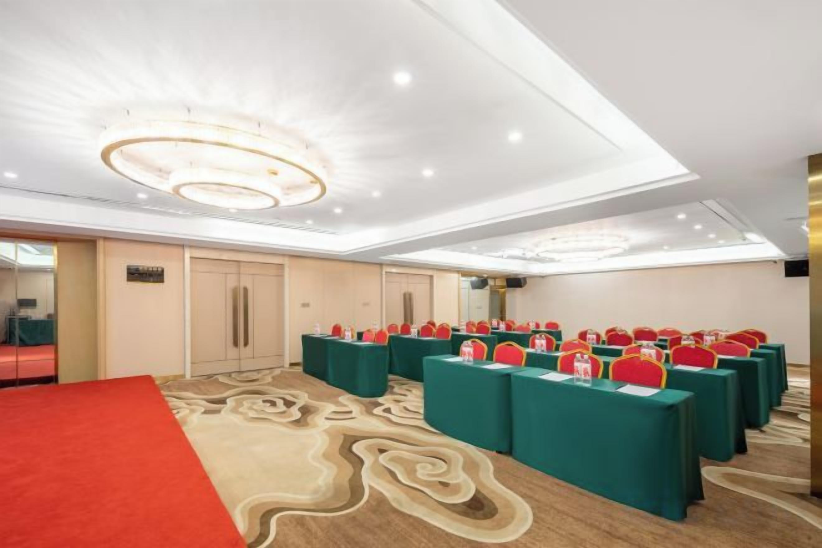 Uma sala de conferências de hotel com uma mesa comprida, várias cadeiras e um tapete vermelho.