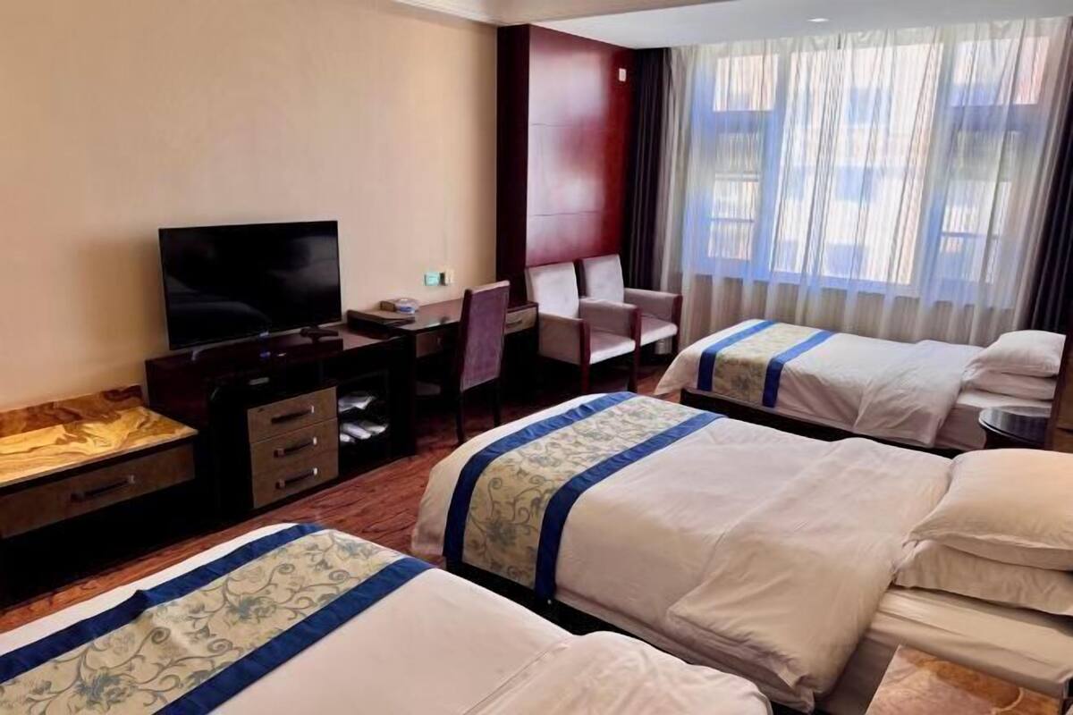 Quarto de hotel com duas camas, televisão, escrivaninha e uma cadeira.