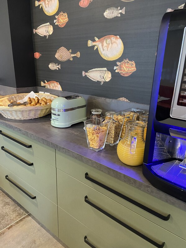 Buffet de café da manhã com diversos alimentos e uma máquina de café.