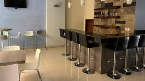 Uma cozinha moderna com área de bar, banquetas e uma televisão de tela plana na parede.