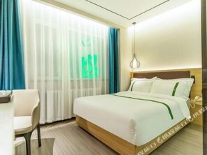 Quarto de hotel com cama, escrivaninha e cadeira.