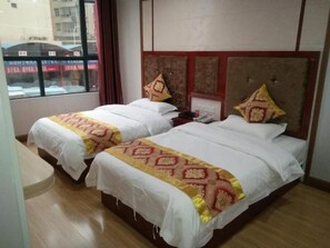 Quarto de hotel com duas camas, cada uma com colcha e almofadas estampadas.