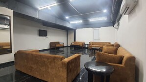 Quarto com sofás, uma mesa redonda e uma televisão de tela plana fixada na parede.