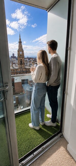 Um casal em pé perto de uma janela com vista para a paisagem urbana, onde se destaca uma torre do relógio.