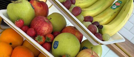 Exposição de frutas com laranjas, maçãs e bananas.