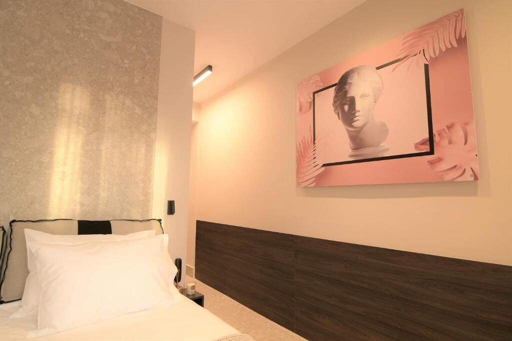 Quarto de hotel com cama, cabeceira, obra de arte na parede e luminária.