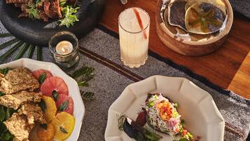 Mesa posta com diversos pratos, incluindo uma salada, carne grelhada e uma bebida.