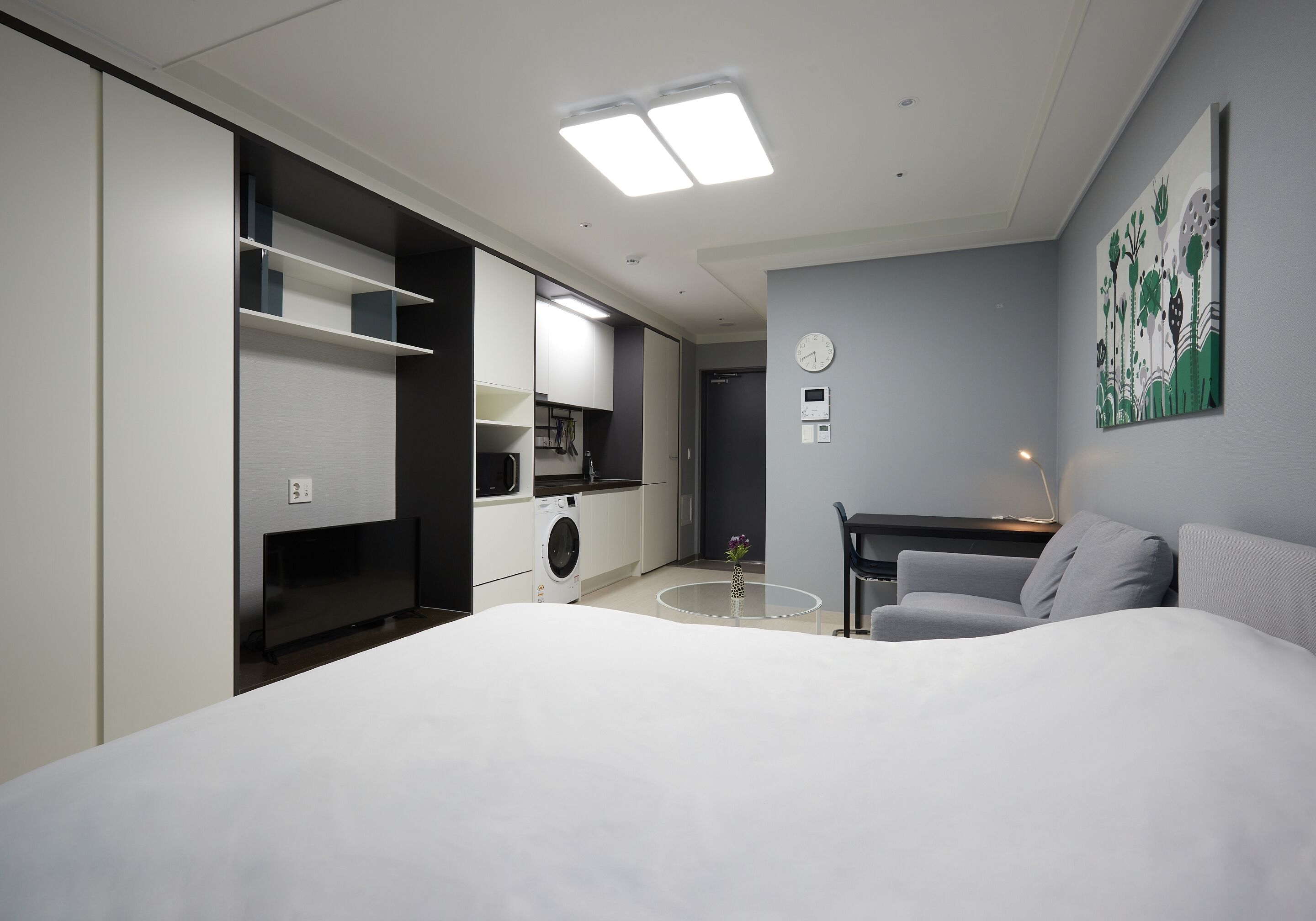 Quarto de hotel moderno com uma cama grande, uma mesa de escritório, uma cadeira, máquina de lavar e área de jantar.