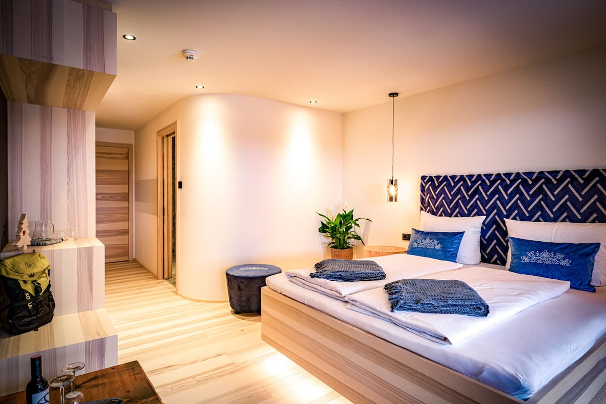 Quarto moderno com uma cama grande, uma mesinha de cabeceira pequena, uma planta em vaso e um lustre.