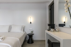 Quarto de hotel moderno com cama, mesa de cabeceira e espaço para café.