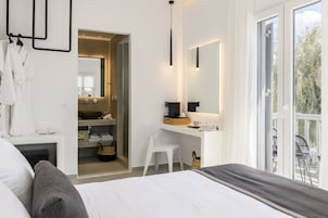 Quarto moderno com uma cama grande, uma escrivaninha pequena, um espelho e vista para o exterior.
