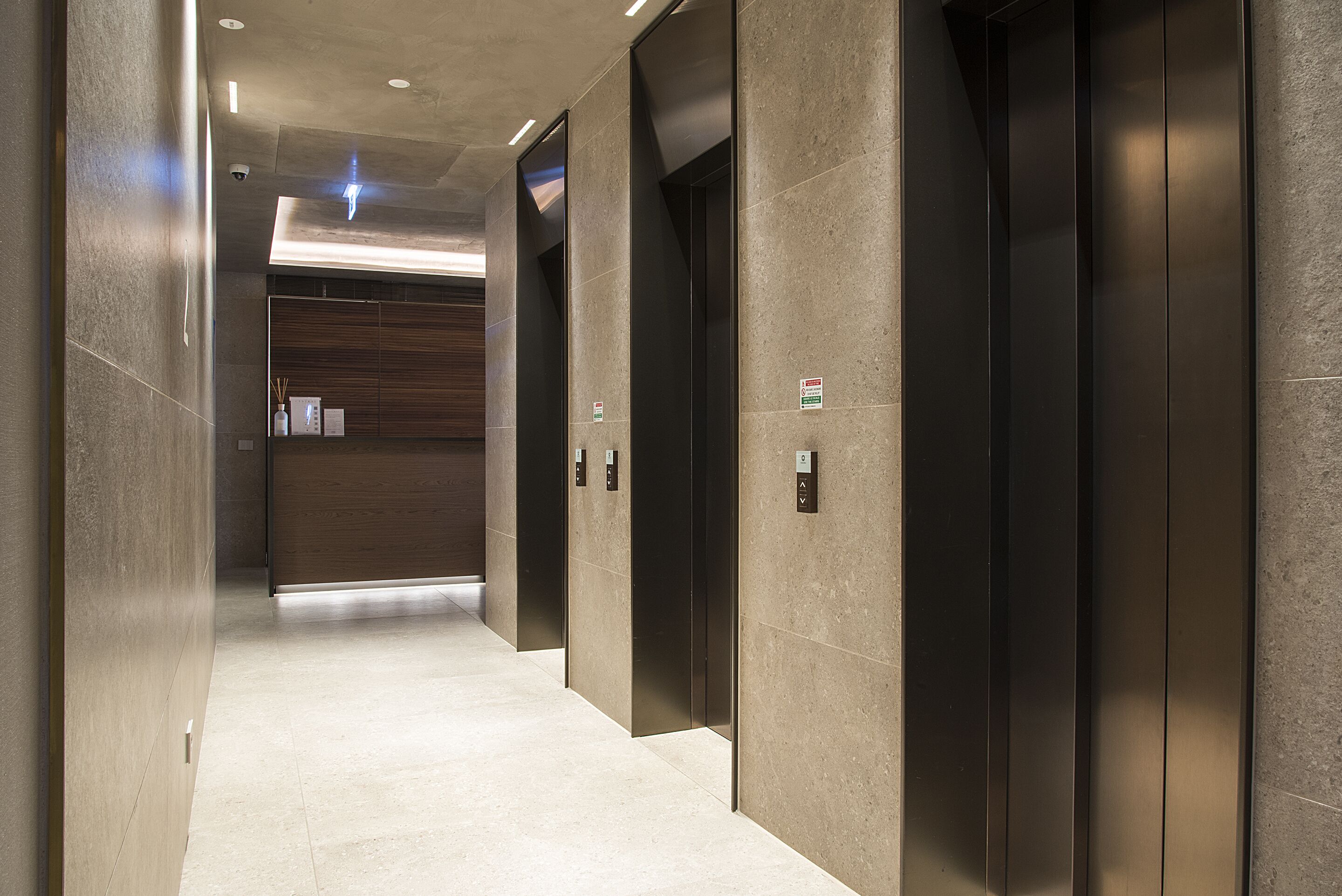 Área de elevador moderna com paredes metálicas e teto iluminado.