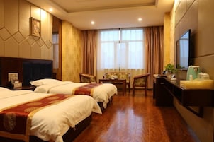 Quarto de hotel com duas camas, uma escrivaninha, uma cadeira, uma televisão e uma janela com cortinas.
