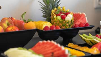 Uma travessa de frutas com maçãs, laranjas, melancia e abacaxi.