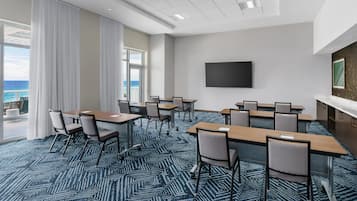 Uma sala de conferências com uma mesa grande, cadeiras e uma televisão na parede.