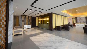 Um lobby moderno com balcão de recepção, área de estar e uma parede decorativa.