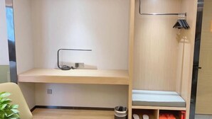 Quarto moderno e compacto com escrivaninha de madeira, um banco e um sapateiro.