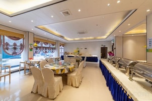 Espaço de refeições com mesas redondas, cadeiras e serviço de buffet.