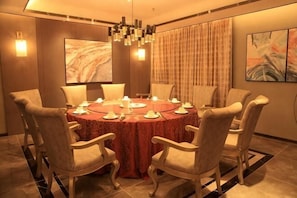 Uma sala de jantar com uma mesa redonda, seis cadeiras e um candelabro.