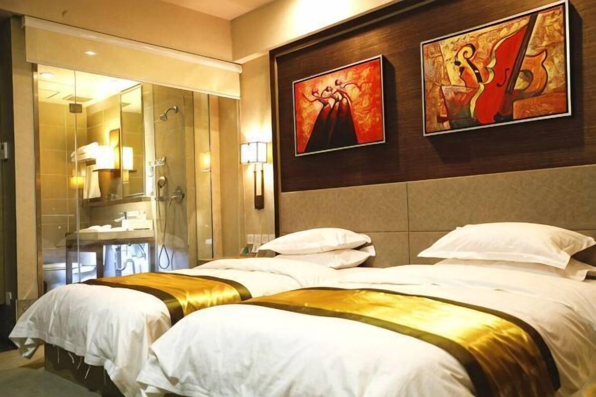 Quarto de hotel com duas camas, um espelho grande e obras de arte na parede.