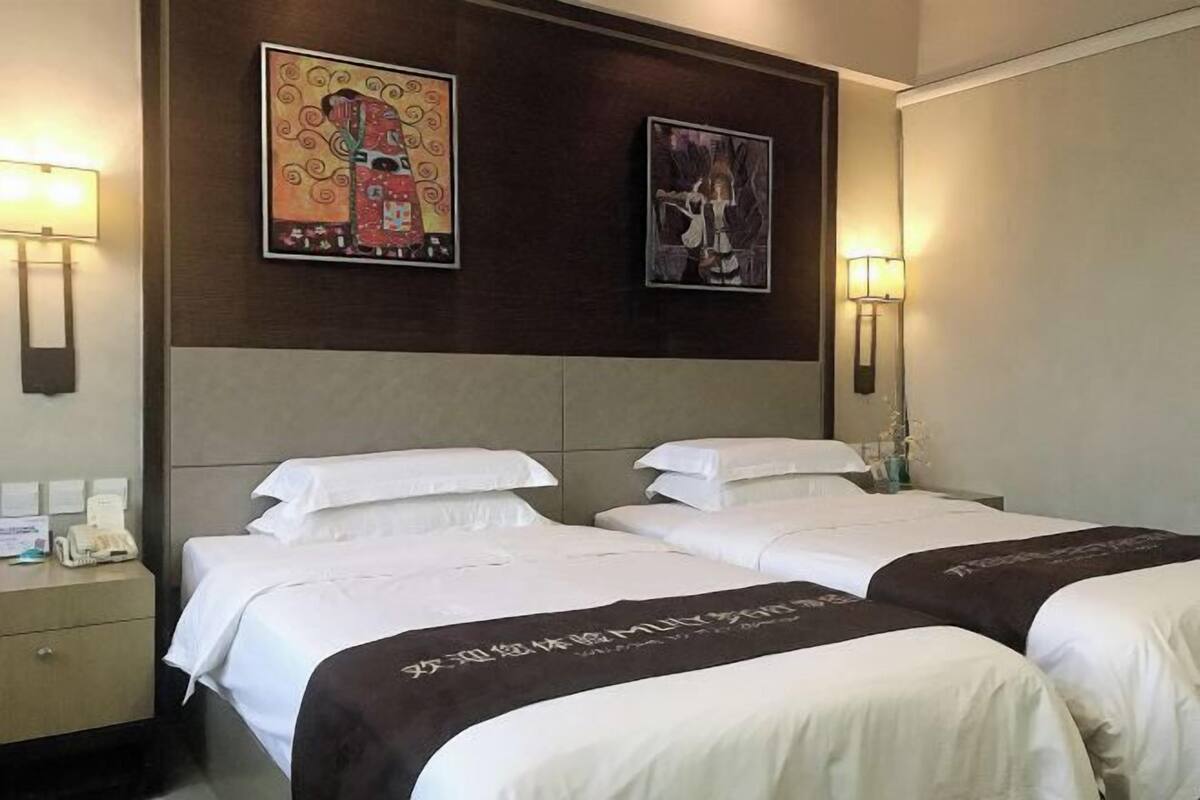 Quarto de hotel com duas camas, uma mesa de cabeceira e uma obra de arte na parede.