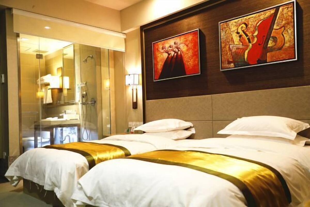 Quarto de hotel com duas camas, chuveiro e obras de arte na parede.