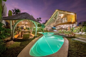 Uma área de piscina moderna com design arquitetônico singular, incluindo uma piscina curvada e um espaço de estar coberto.