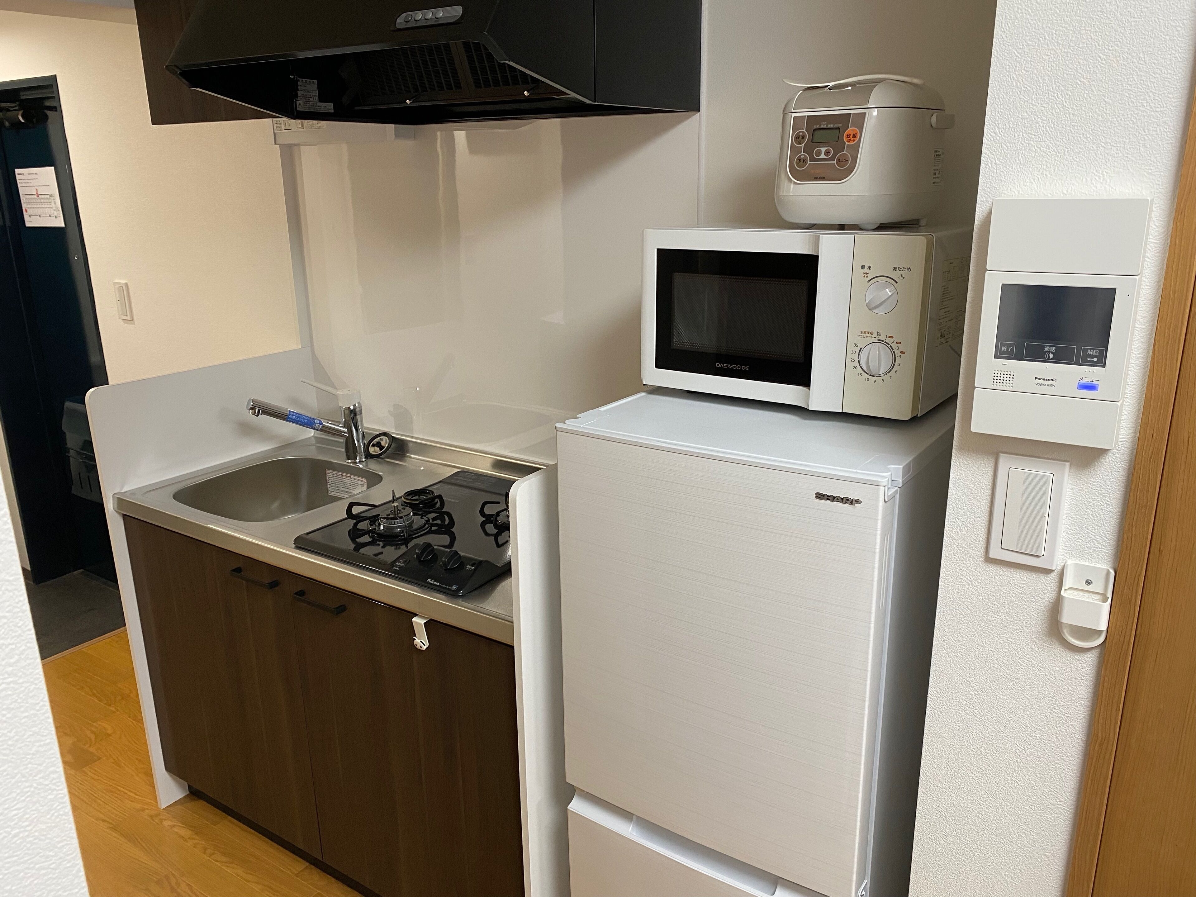 Uma cozinha compacta com fogão a gás, micro-ondas e geladeira.