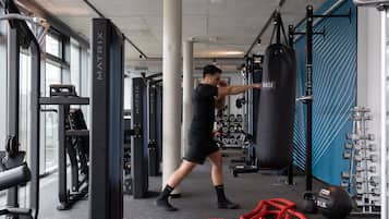 Uma academia com equipamentos de ginástica, um saco de pancadas e acessórios para musculação.