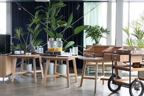 Um interior moderno com móveis de madeira, plantas em vasos e um carrinho com caixas organizadoras.