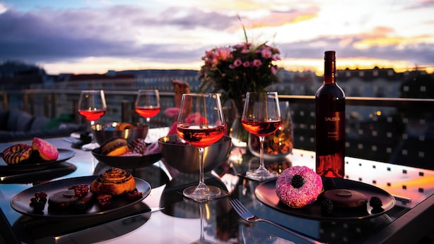 Uma mesa posta para refeição, com pratos de comida, copos de vinho tinto e uma garrafa de vinho.