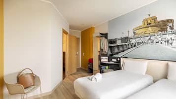 Quarto de hotel com uma cama, uma cadeira, um porta-roupas e um mural na parede retratando um edifício histórico.