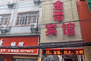 Um edifício com várias placas, incluindo uma com caracteres chineses e outra com um número de telefone.