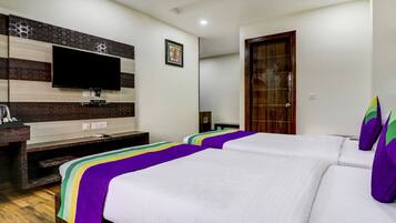 Quarto de hotel com duas camas, uma televisão fixada na parede, um armário de madeira e uma porta com espelho.