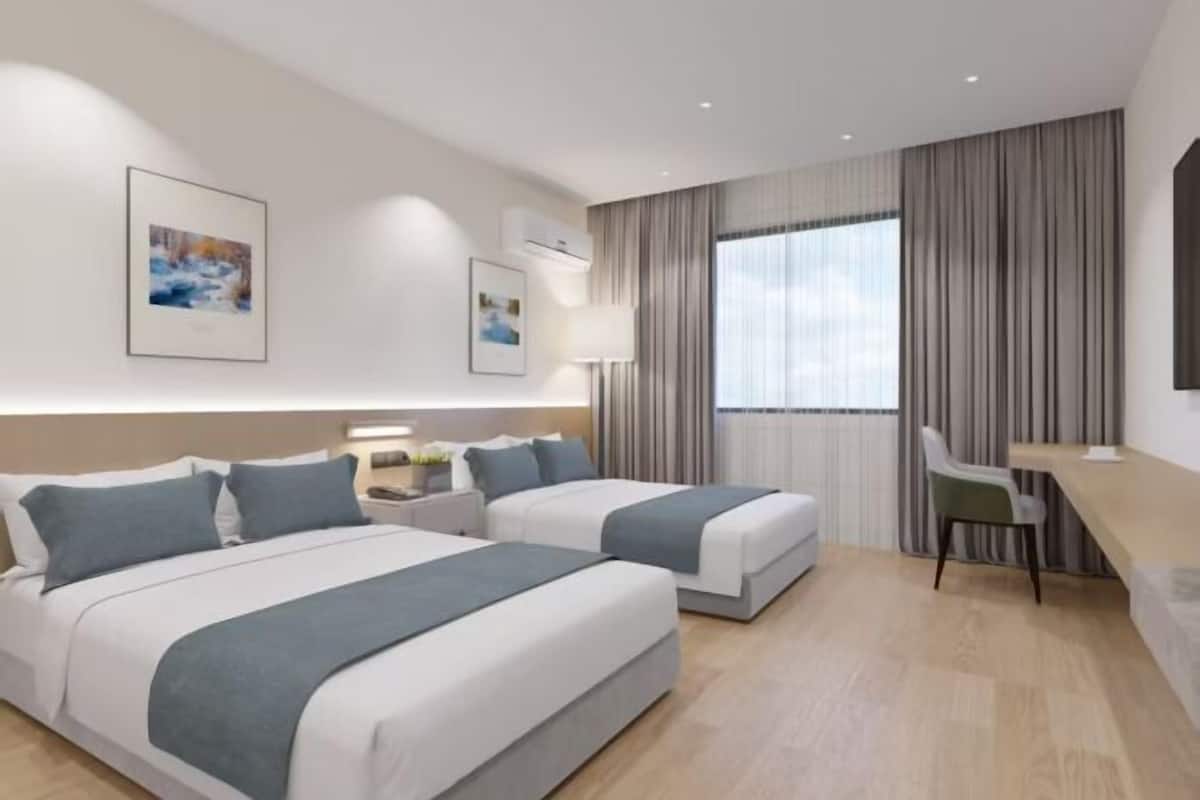 Quarto moderno de hotel com duas camas, uma escrivaninha e uma cadeira.