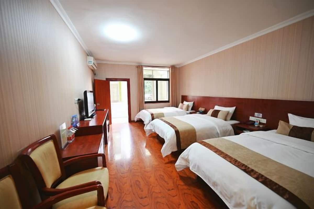 Quarto de hotel com duas camas, uma escrivaninha com cadeira, televisão e janela.