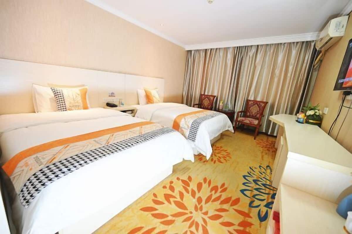Quarto de hotel com duas camas, uma escrivaninha e uma cadeira.