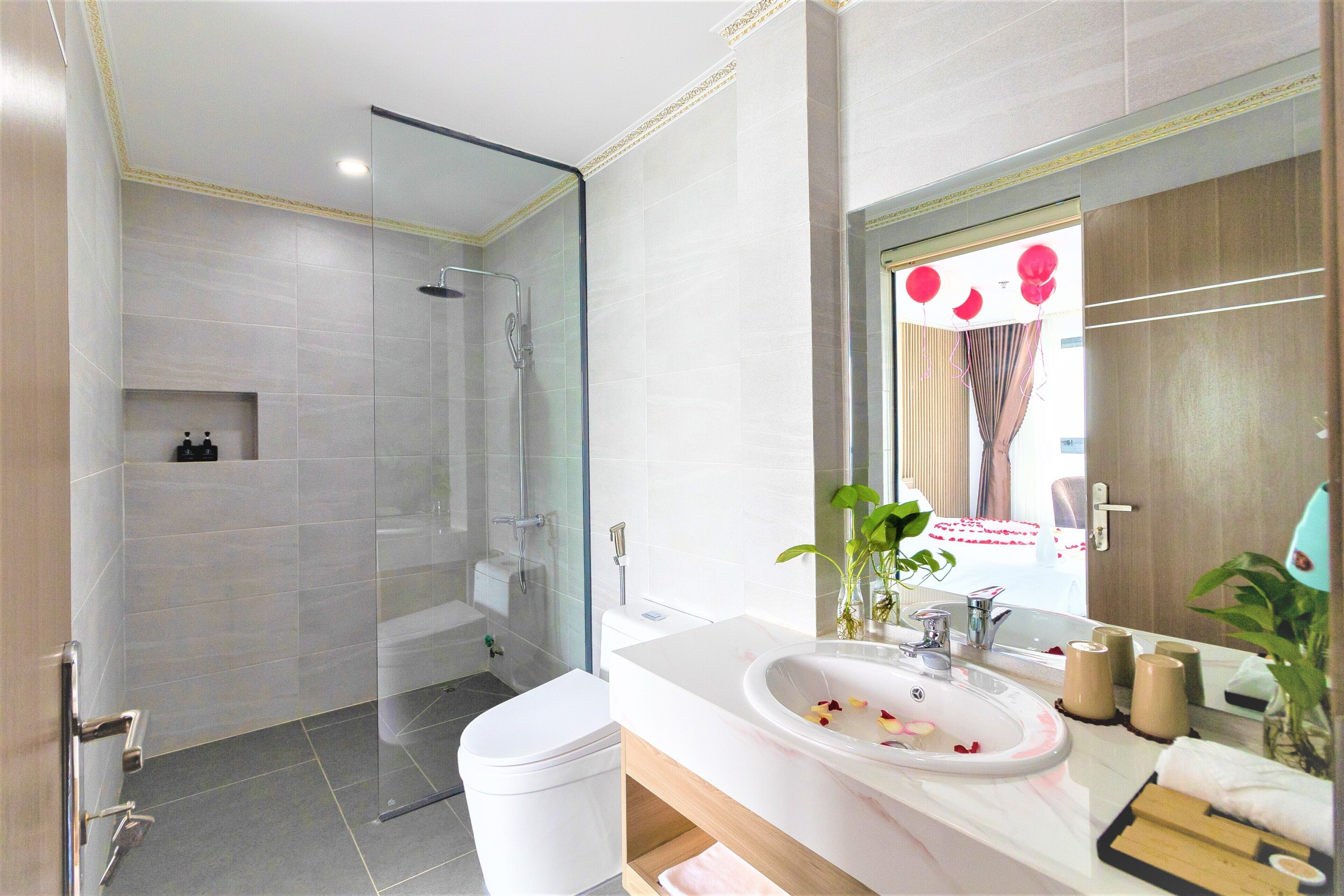 Casa de banho moderna com cabine de chuveiro em vidro, sanita branca e toucador com lavatório e espelho.